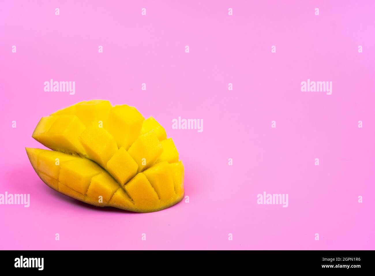 Fresh ripe mango on a pink background. Half a sliced mango on a pink ...