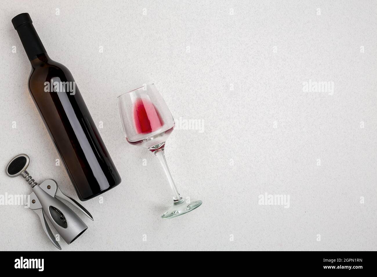 Overhead angled view of a large bottle of red wine, drinking glass on ...