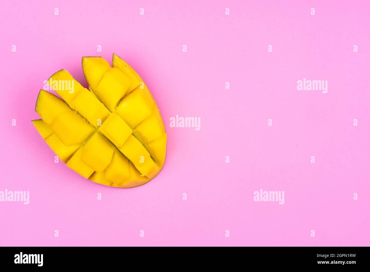 Fresh ripe mango on a pink background. Half a sliced mango on a pink ...