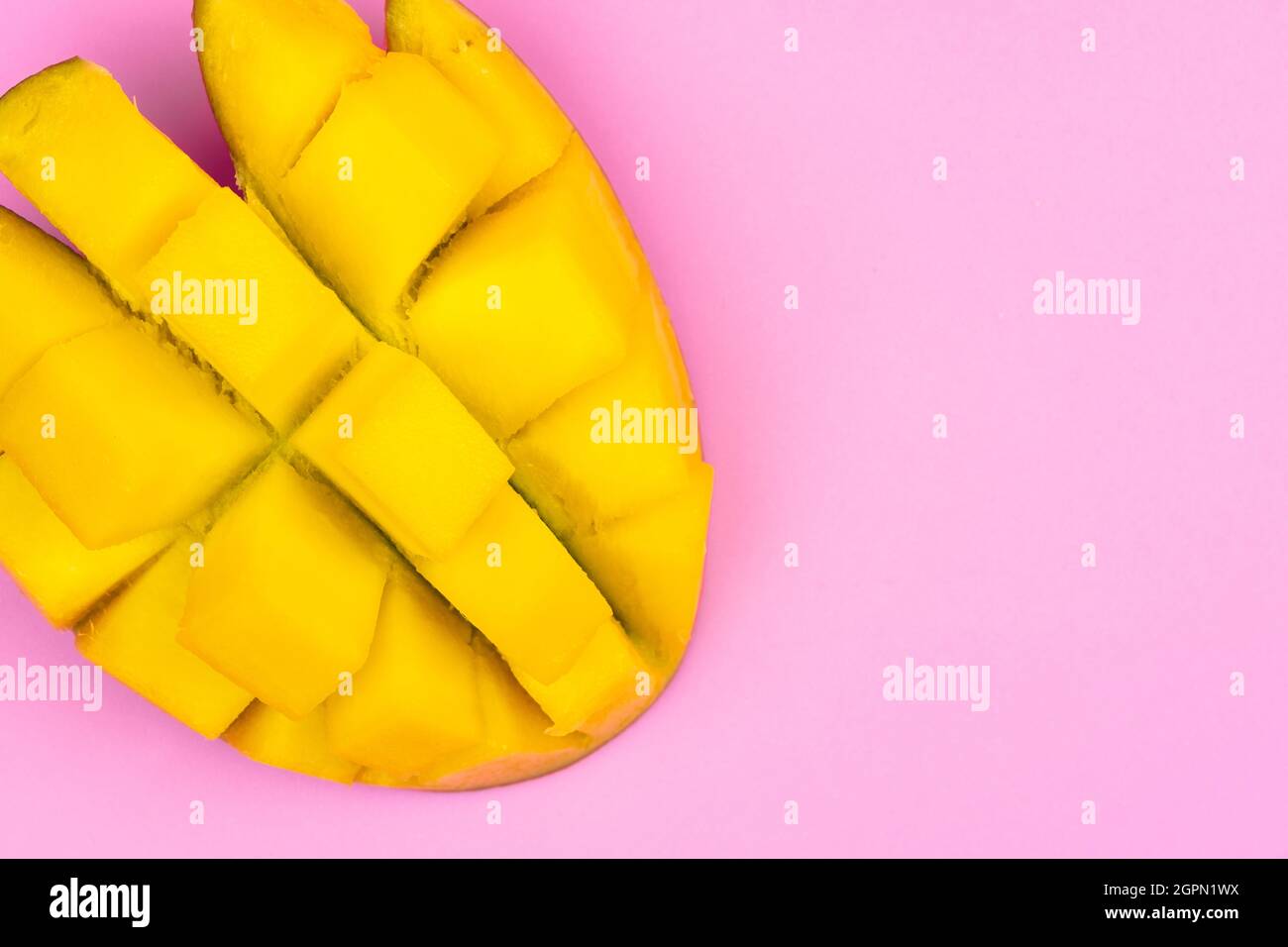 Fresh ripe mango on a pink background. Half a sliced mango on a pink ...