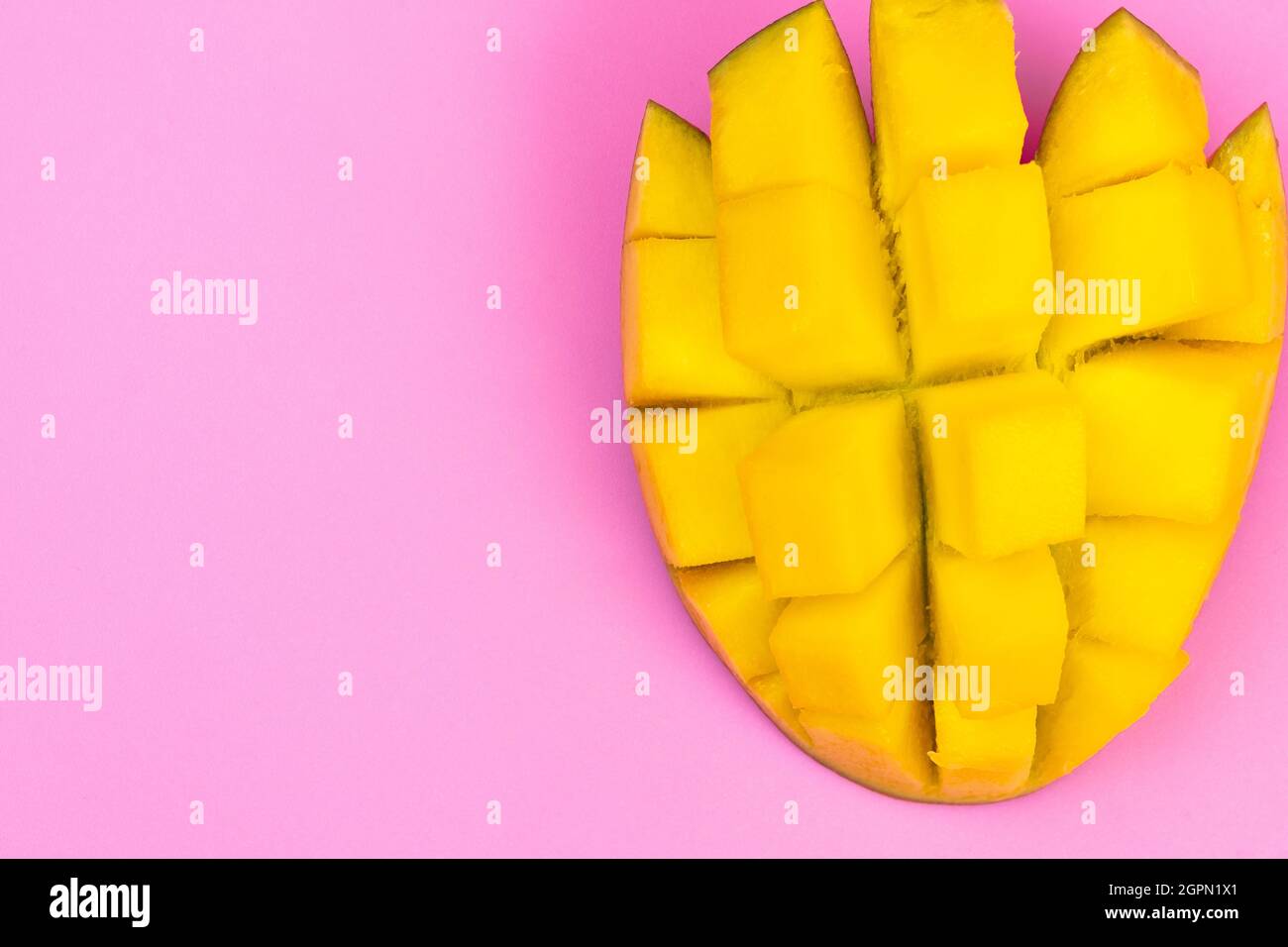 Fresh ripe mango on a pink background. Half a sliced mango on a pink ...