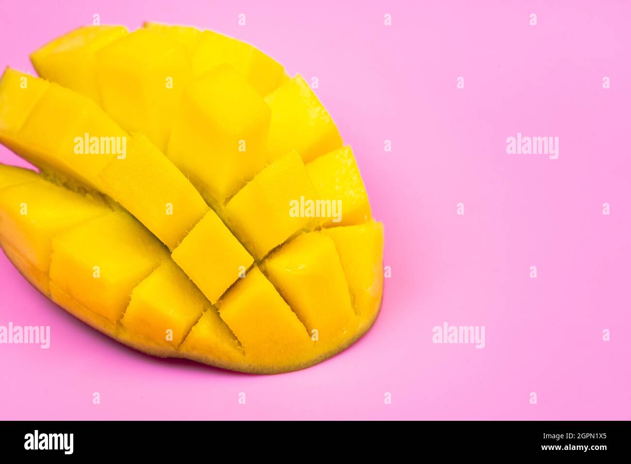 Fresh ripe mango on a pink background. Half a sliced mango on a pink ...