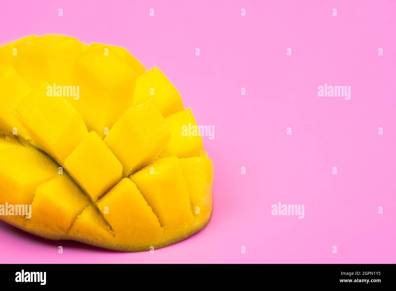 Fresh ripe mango on a pink background. Half a sliced mango on a pink ...