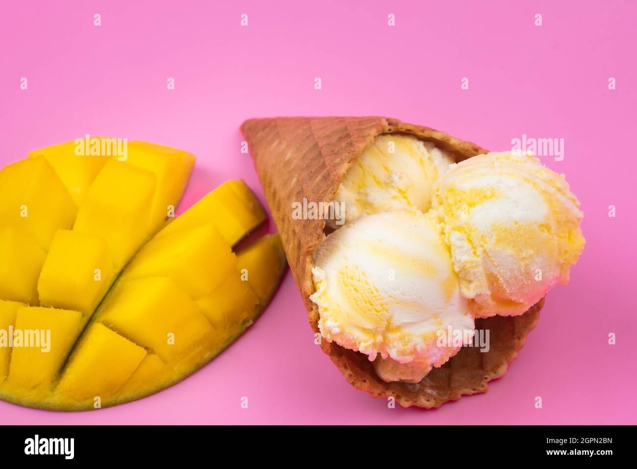 Mango-flavored ice cream balls in a waffle cone on a pink background ...