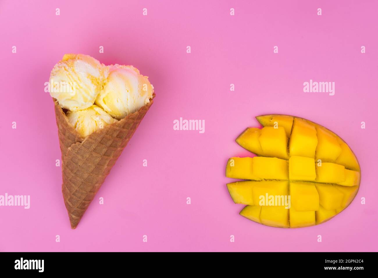 Mango-flavored ice cream balls in a waffle cone on a pink background ...