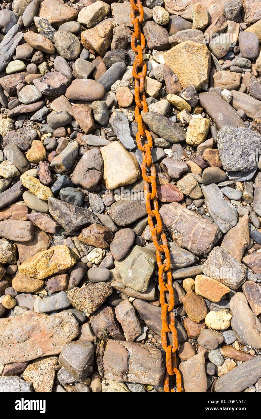 An old rusty chain on a background of rocks of all colors at low tide ...