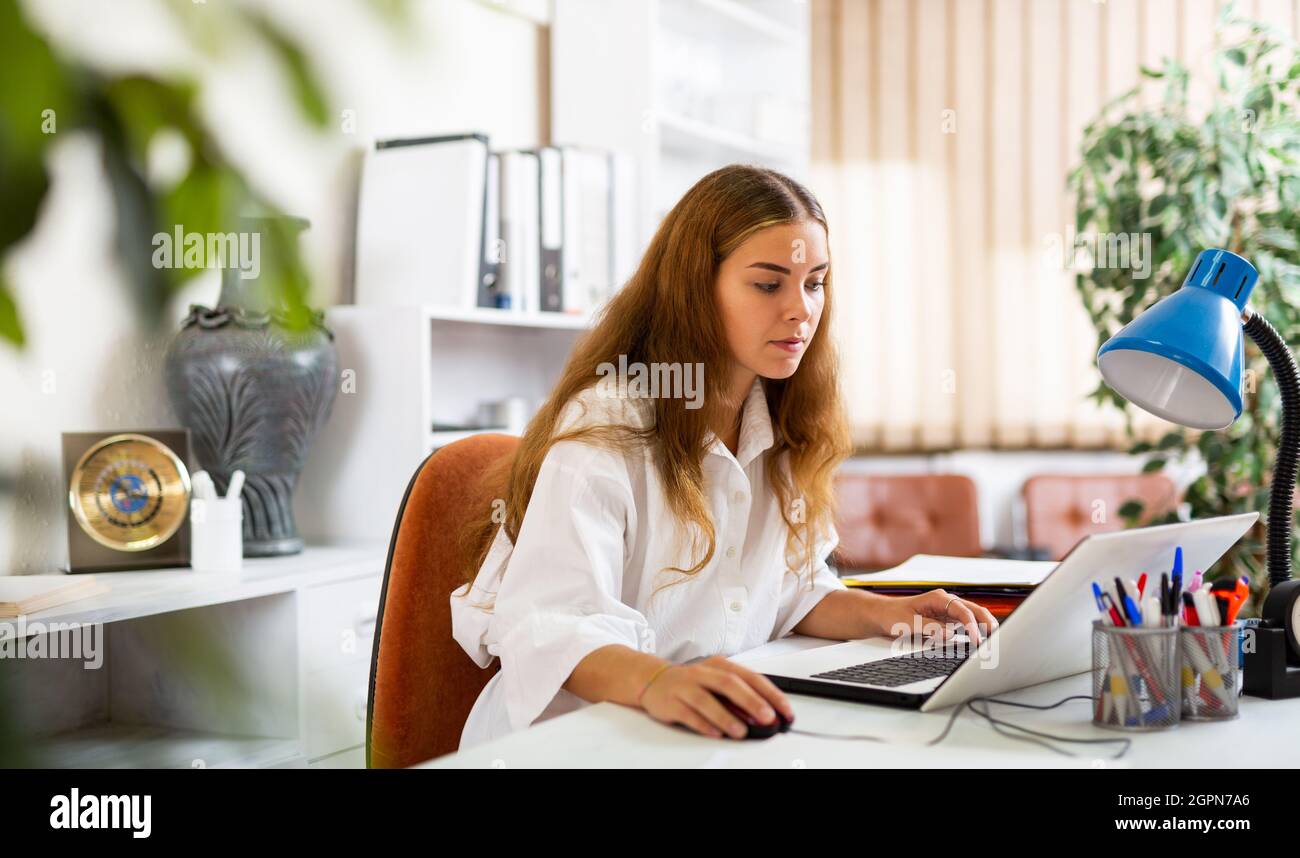 Portrait of focused young woman working at office desk. Daily work ...