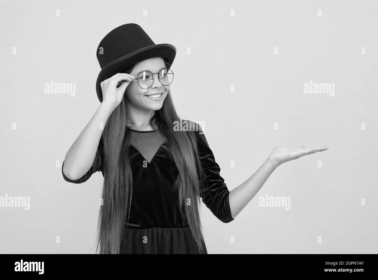 Presenting product. Happy girl hold empty hand yellow background ...