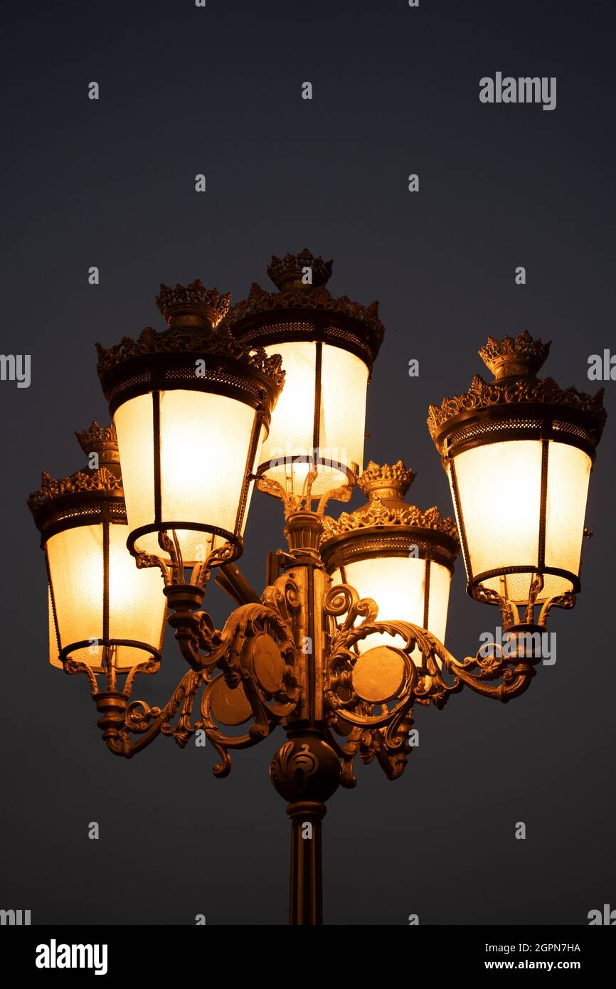 closeup view of vintage old street light with iron arms shining in the ...