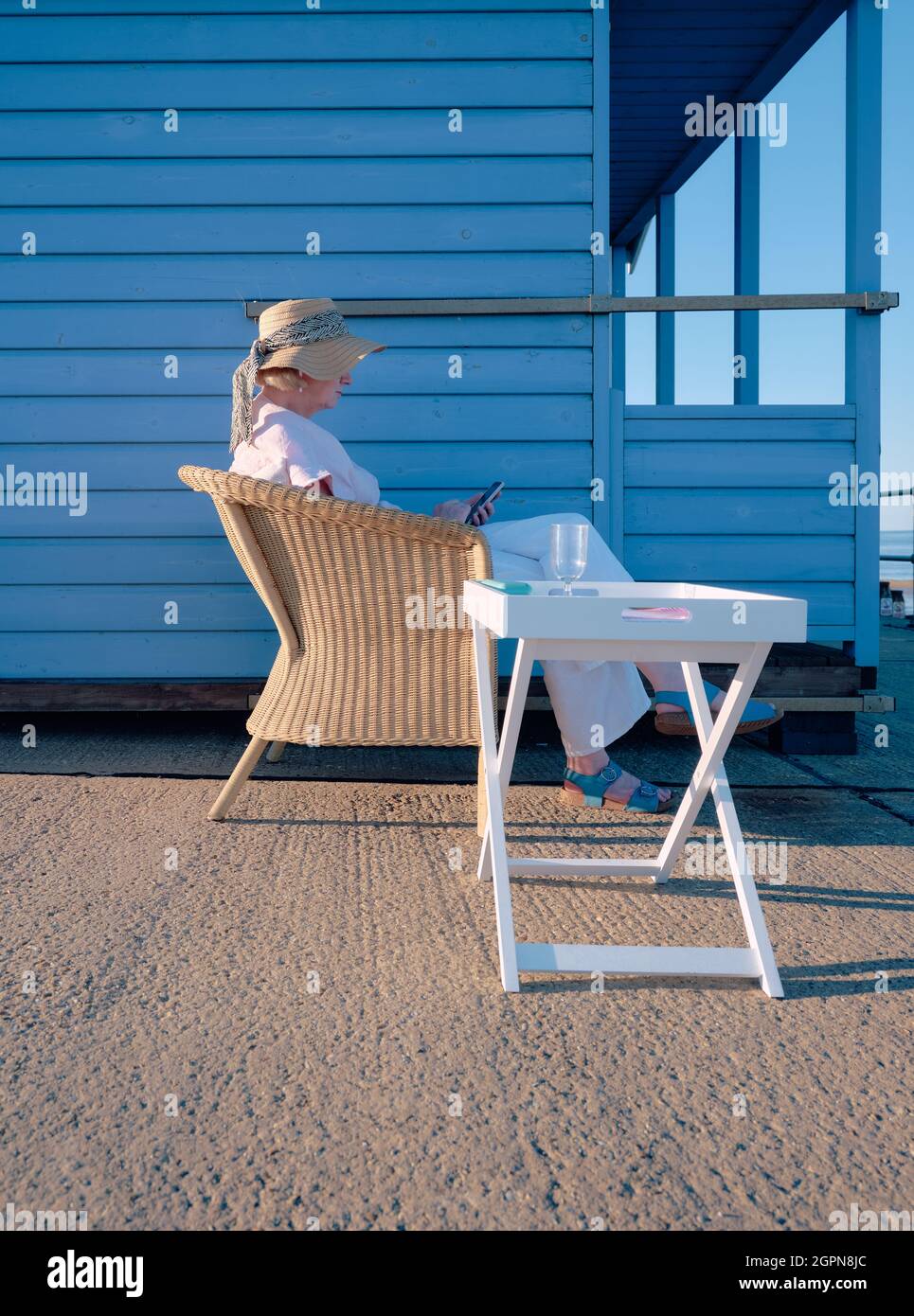 A retired lady enjoying the late evening summer sun outside her blue ...
