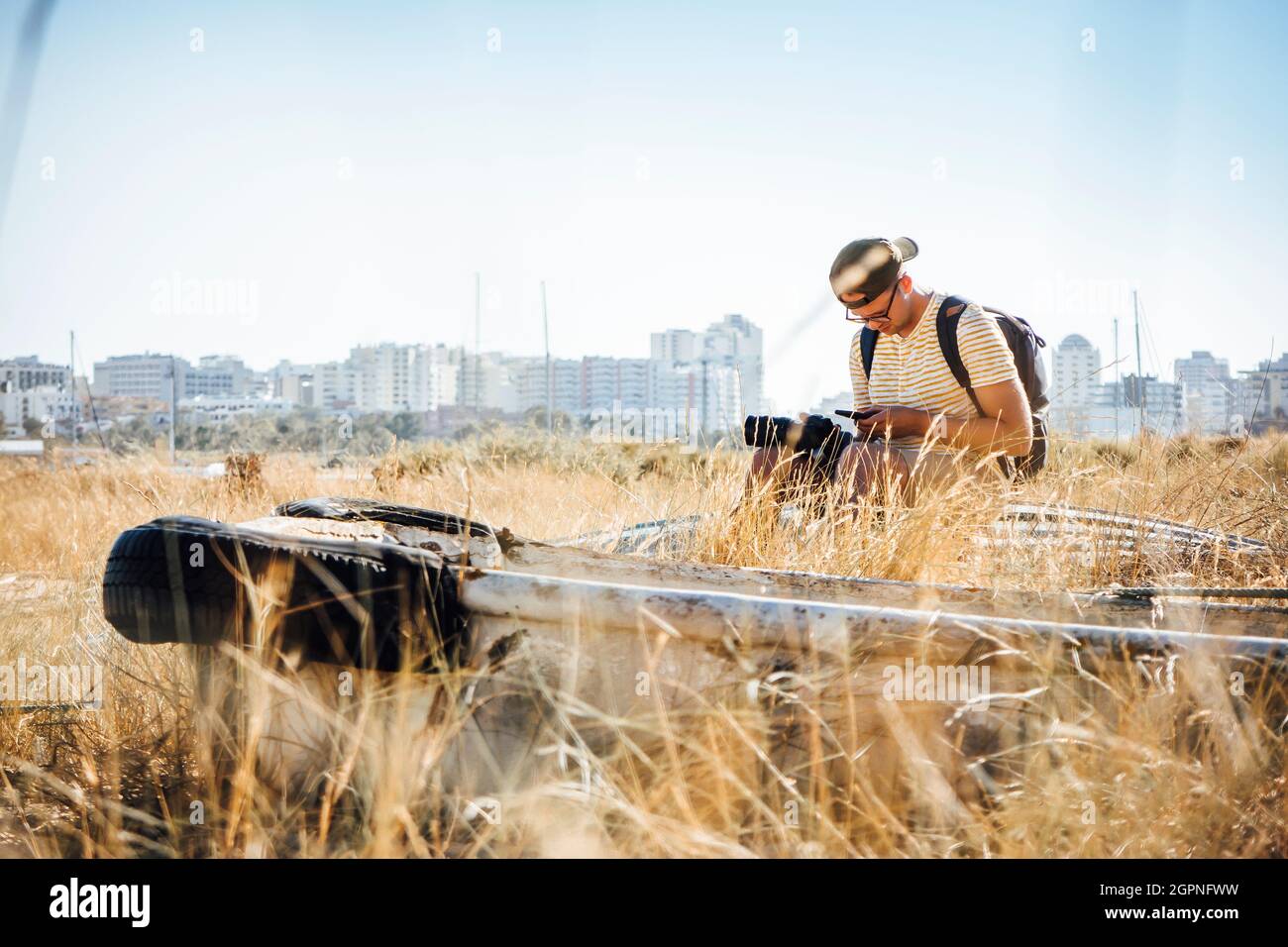 Tourist with a camera and phone sitting among dry grass, Portugal Stock ...