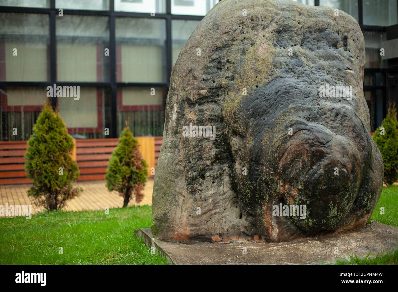 Stone in the city. A wet giant shard of rock is installed on the street ...