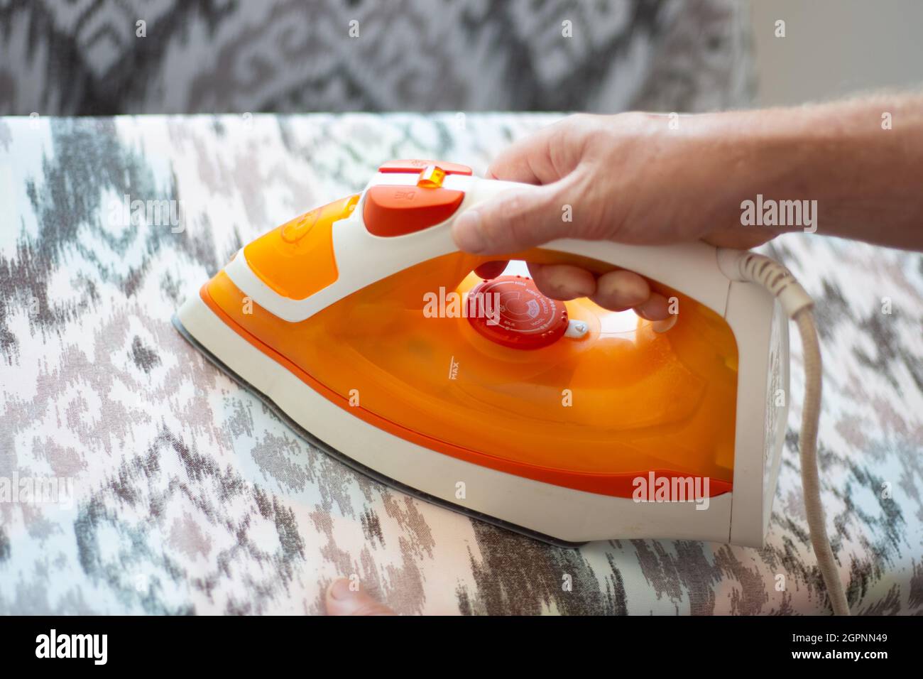 A man ironing linen with an electric iron on an ironing board. Help ...