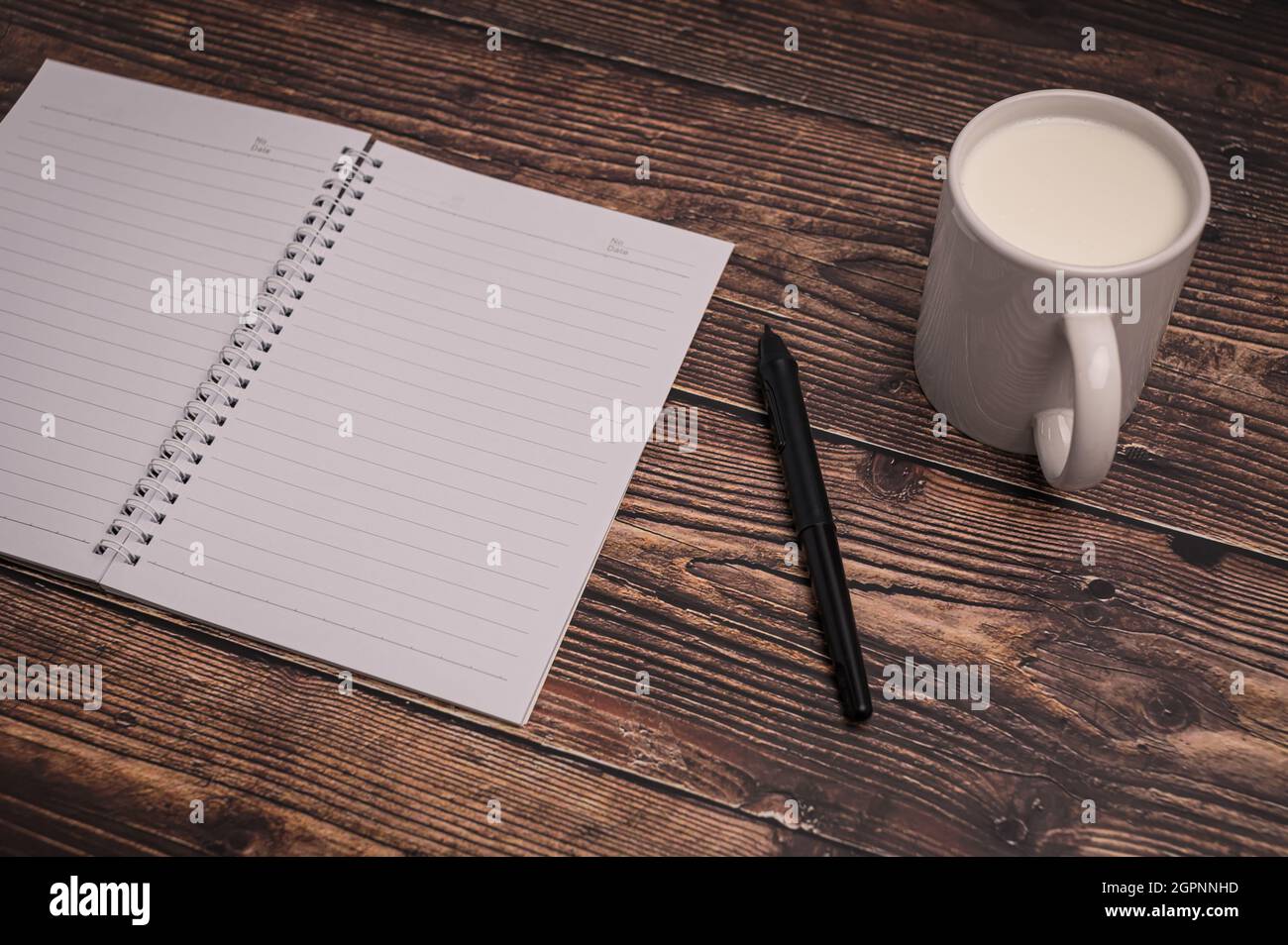 The notebook and a glass of milk are on the desk Stock Photo - Alamy