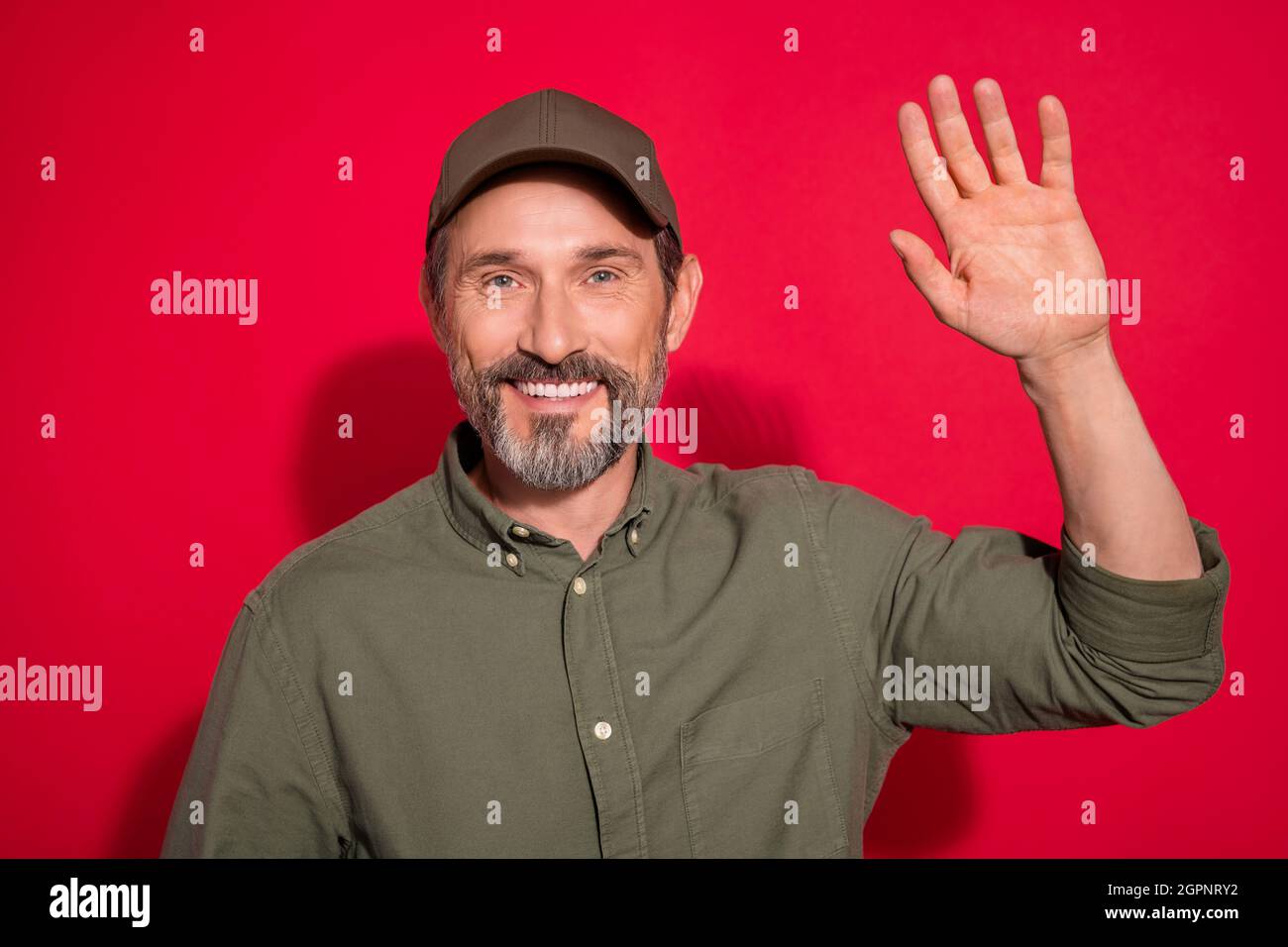 Photo portrait man wearing cap waving hand isolated vibrant red color ...