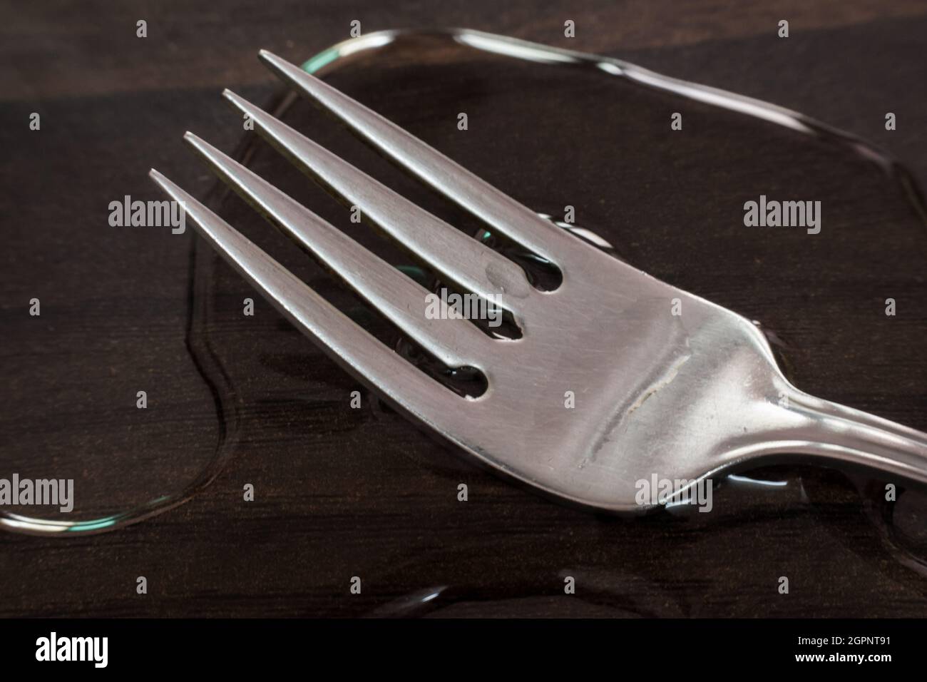 Close up of a steel fork placed against a wood surface of water Stock ...