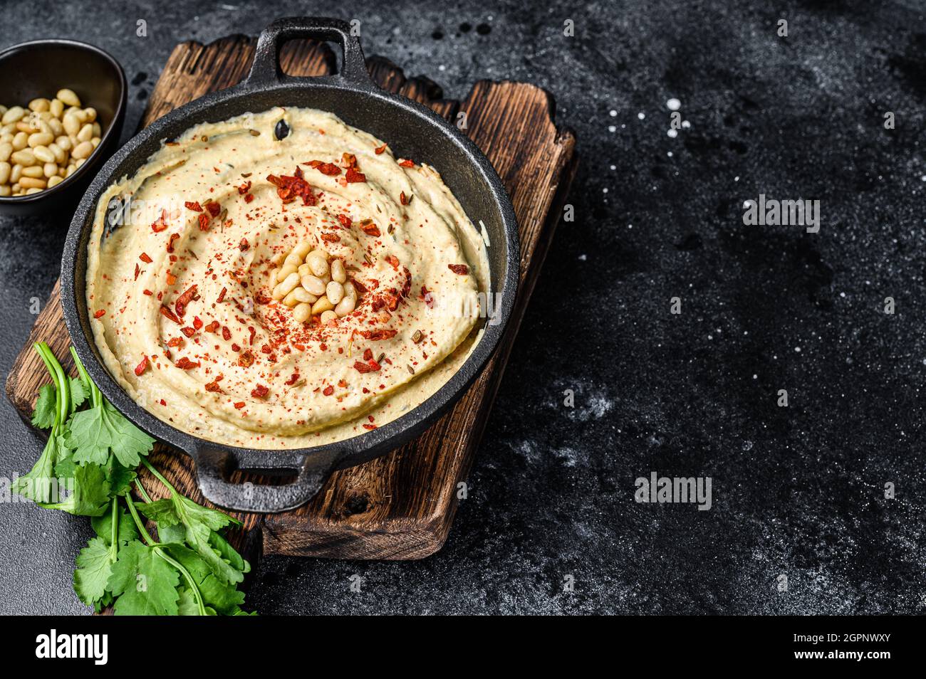 Hummus paste with chickpea and parsley in a bowl. Black background. Top ...