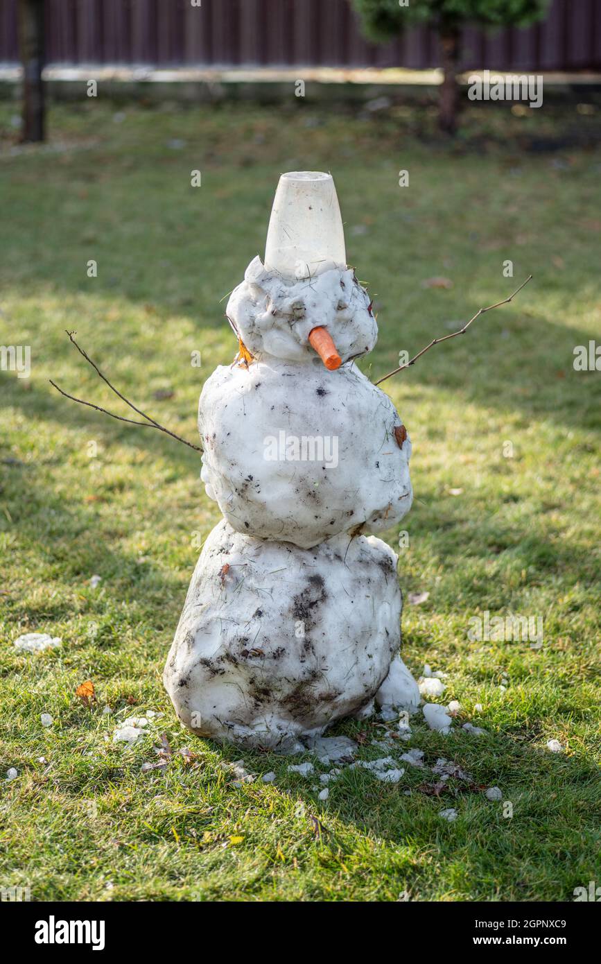 Melting snowman stands on the green grass. The concept of the coming of ...