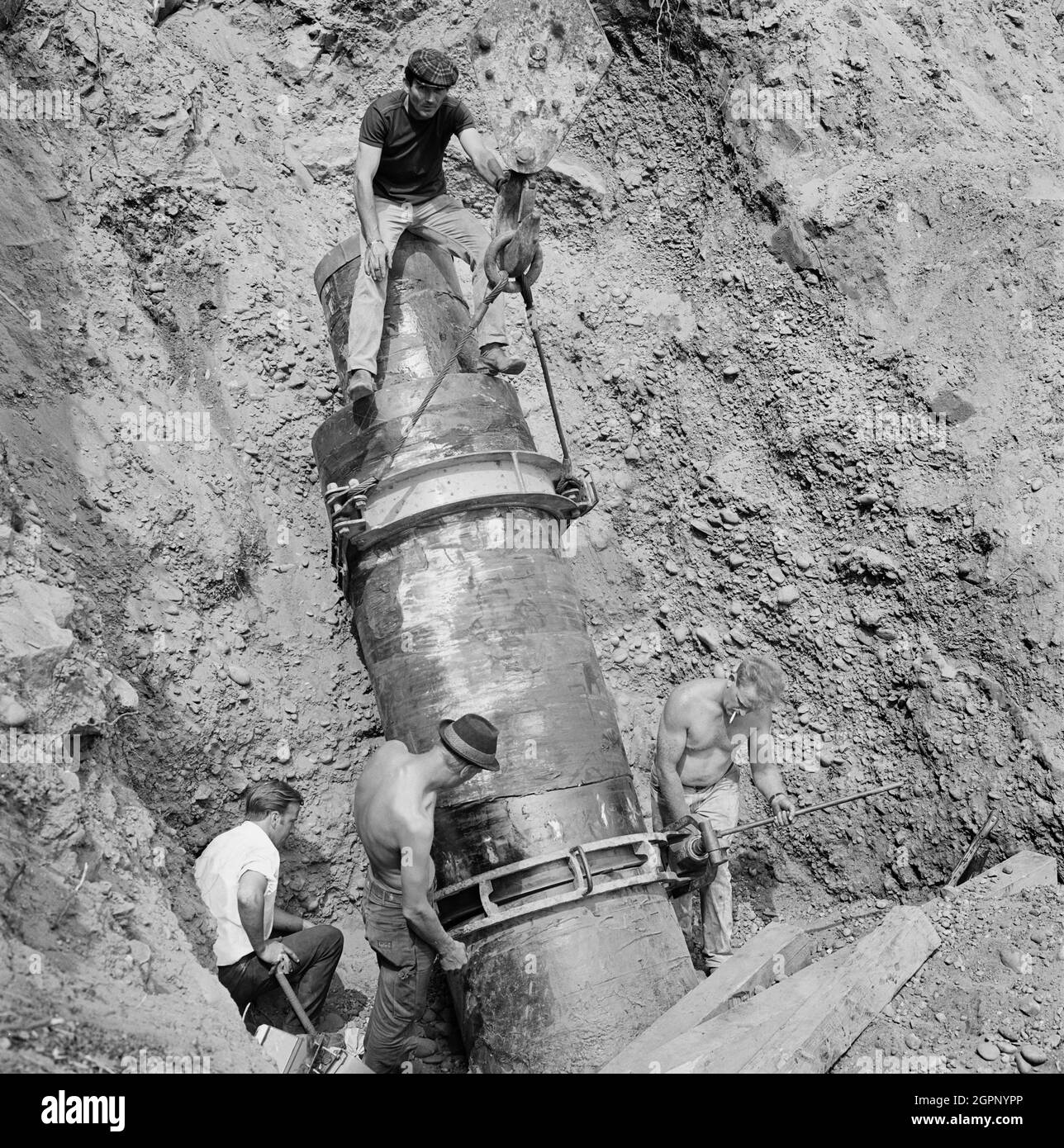 A team of men installing the Barlaston pipeline against a steep and ...