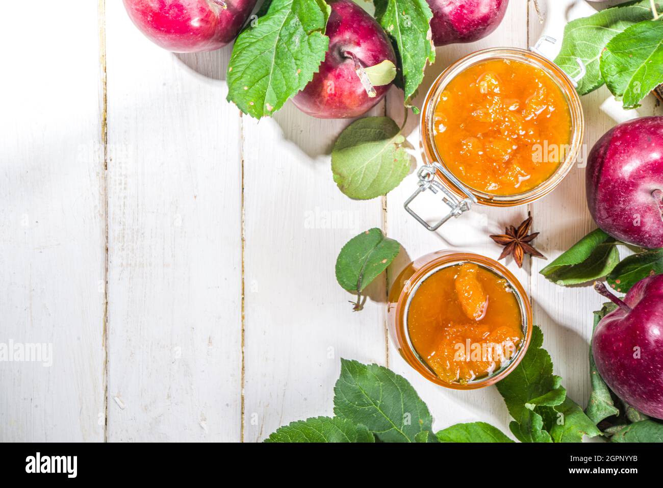 Homemade golden colored apple jam, with farm red apples and leaves on ...