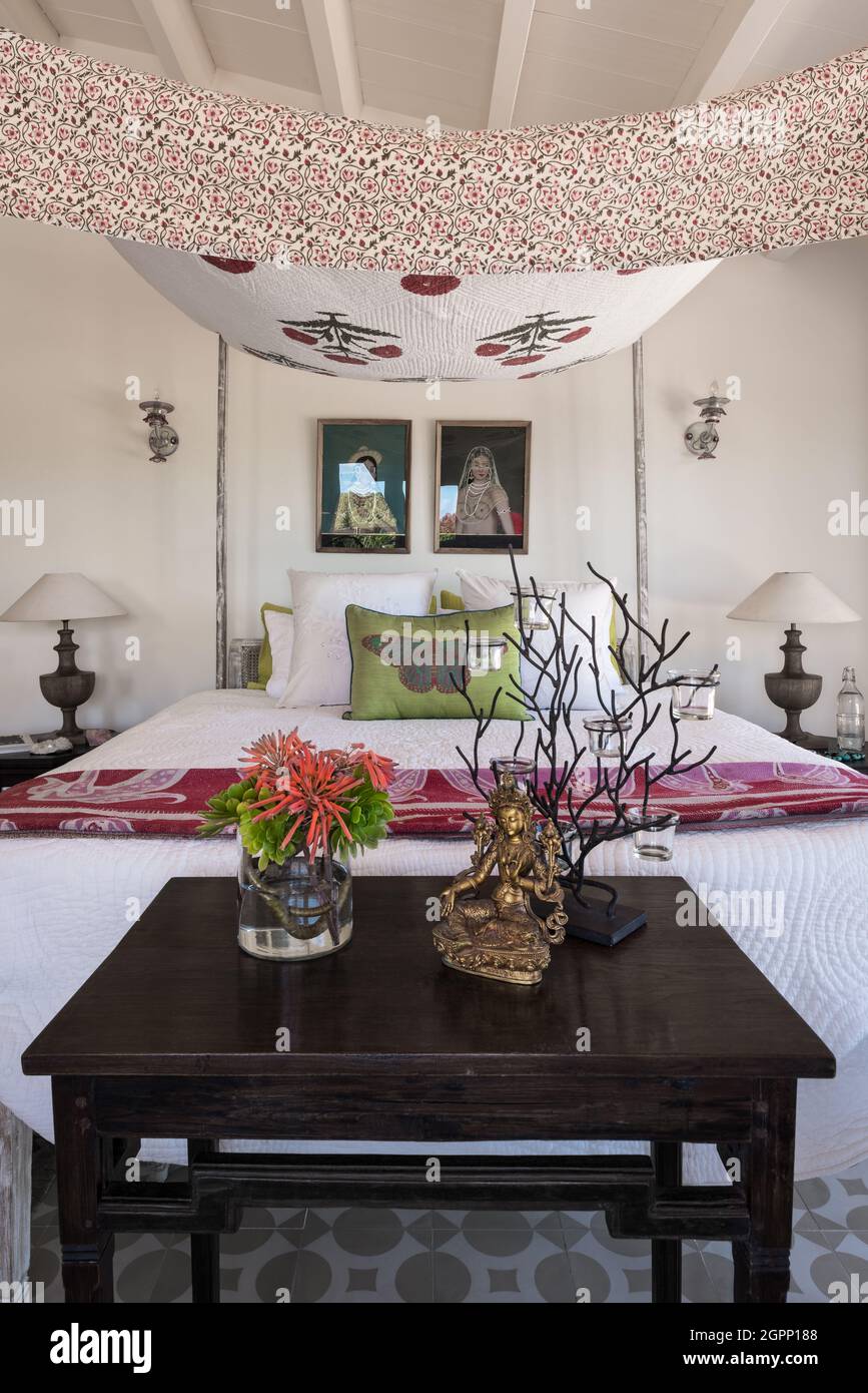 Floral canopy on Goan four poster bed with ornaments on table in ...