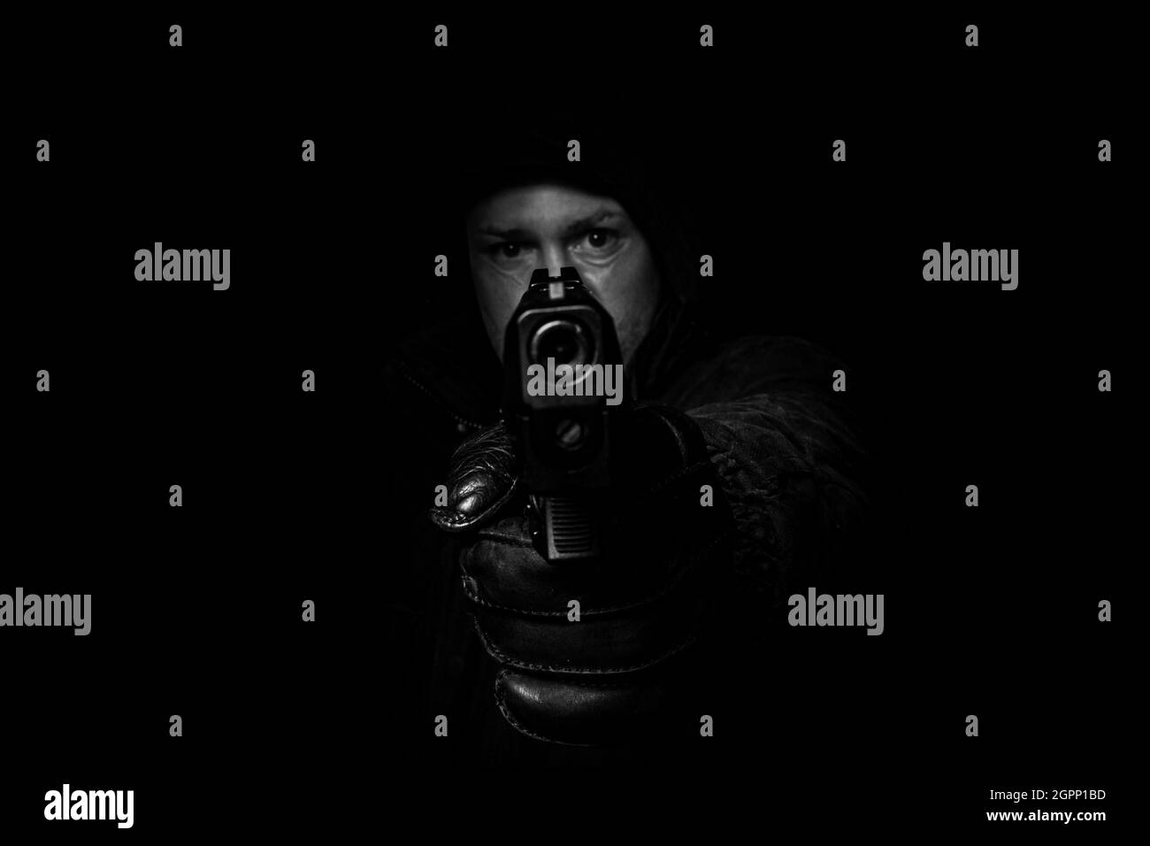 Man standing behind a gun on a dark black background Stock Photo - Alamy