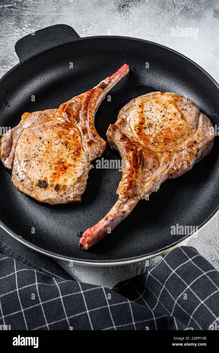 Fried tomahawk pork chop meat steak in a pan. White background. Top ...