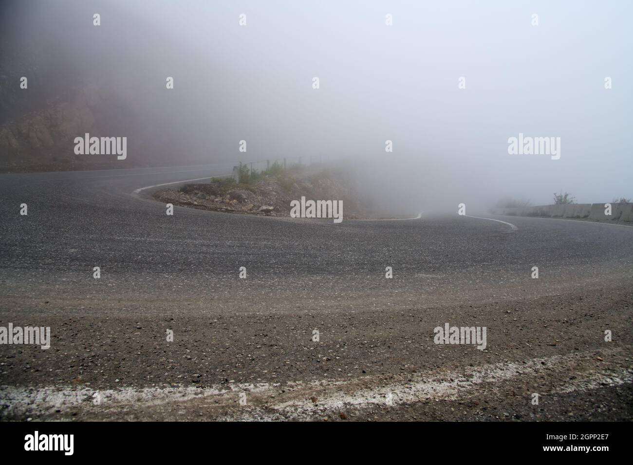Serpentine tar road covered with morning mist in high mountain of ...