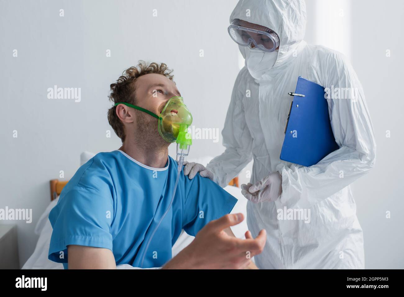doctor in hazmat suit with clipboard near smiling patient in oxygen ...
