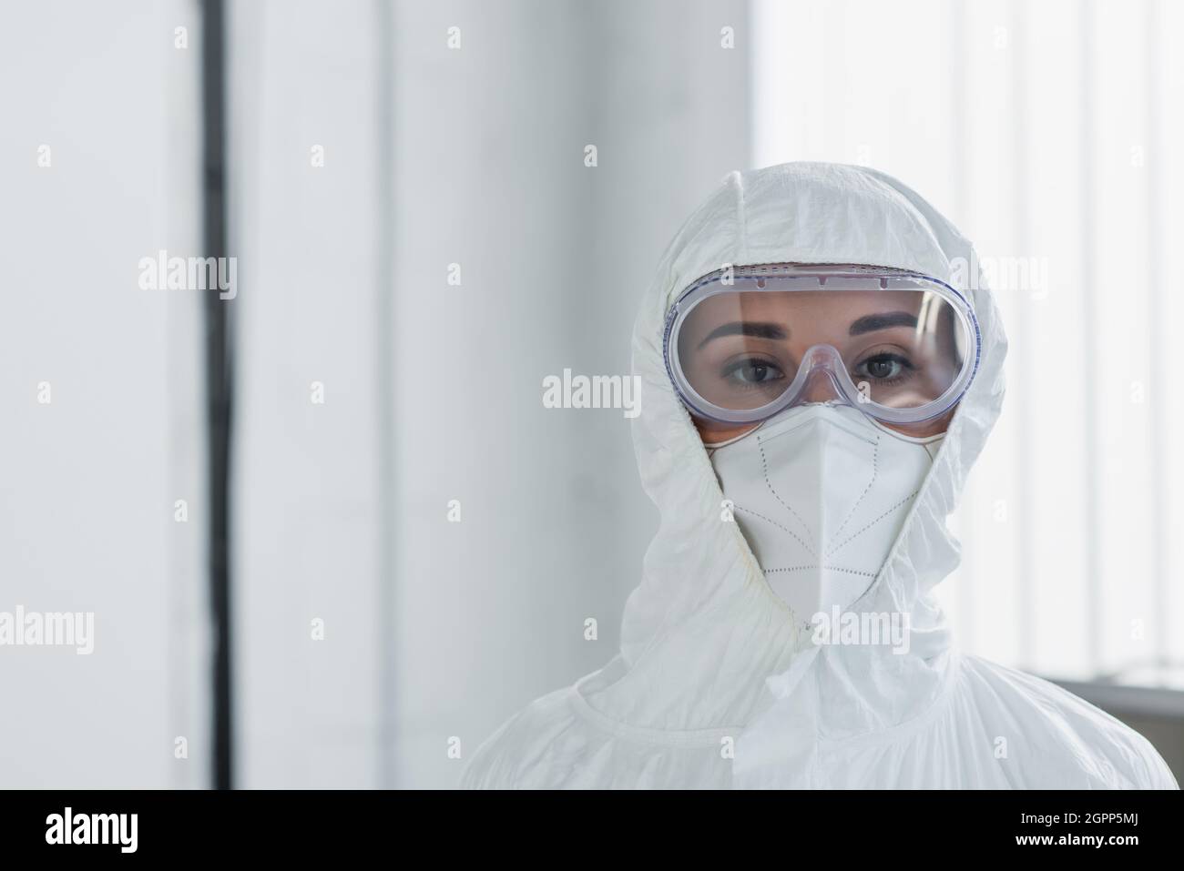 doctor in personal protective equipment and goggles looking at camera ...