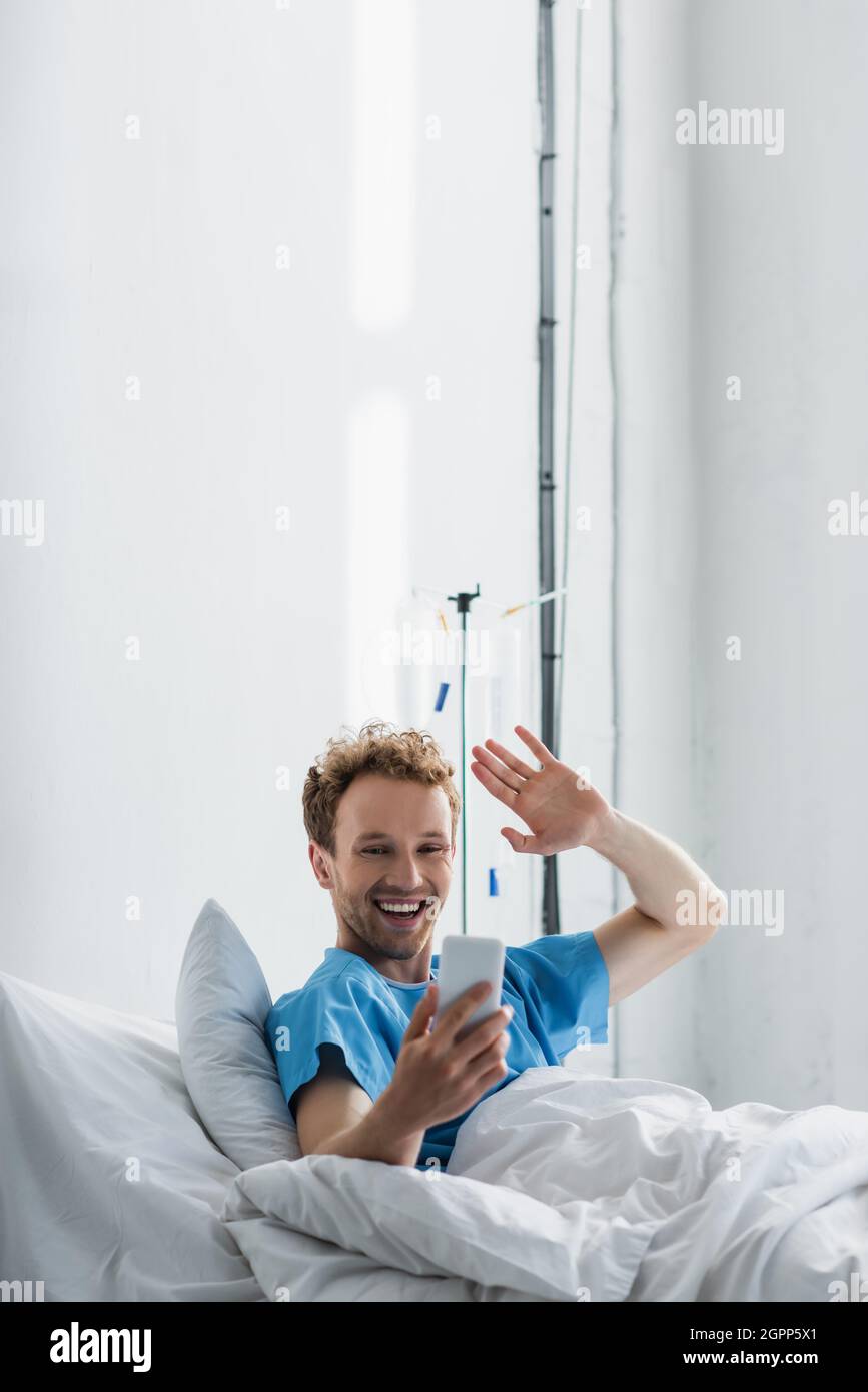 happy patient waving hand while having video call on smartphone in ...
