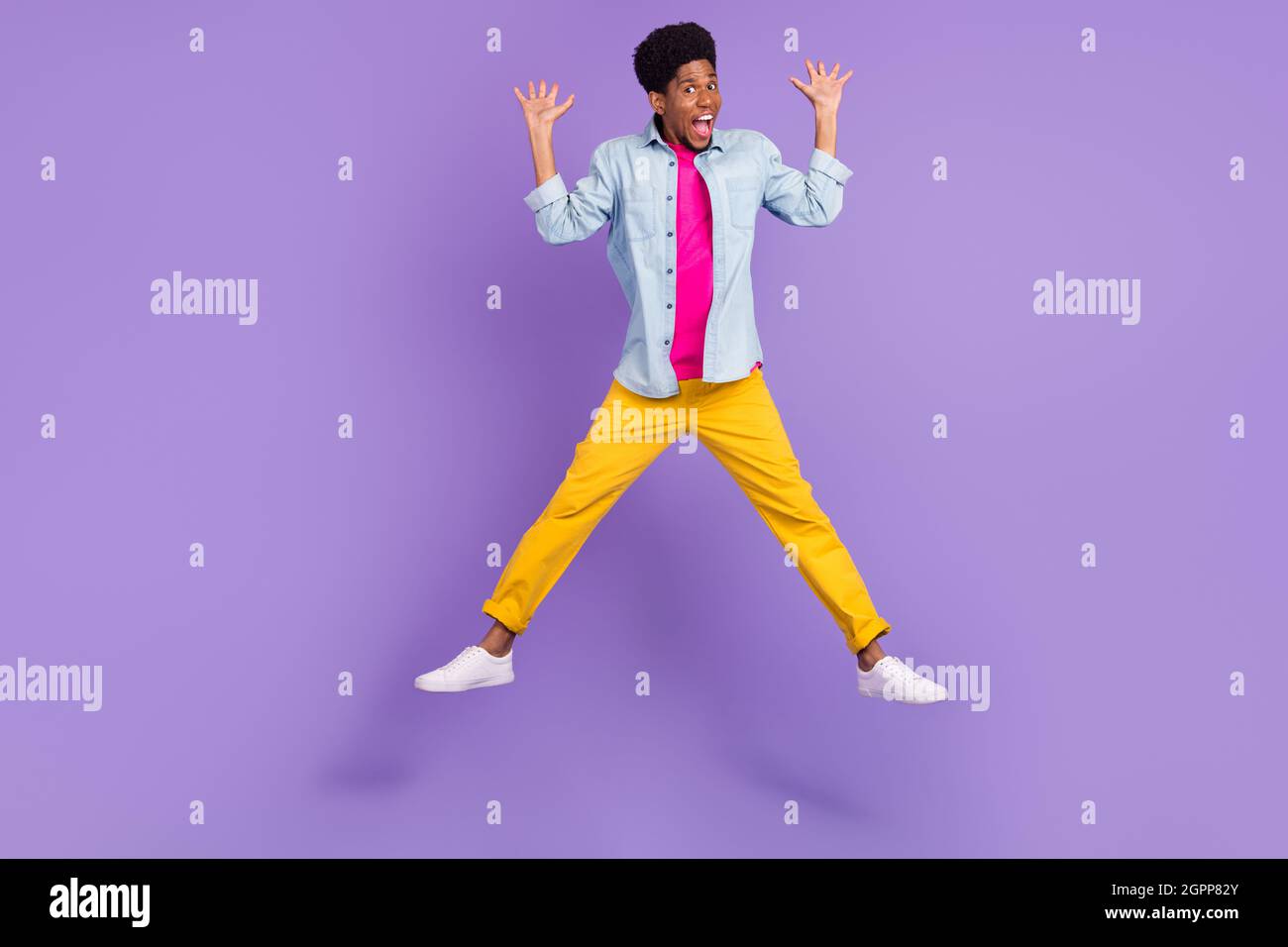 Photo of crazy excited guy jump have fun raise palms scream wear blue ...