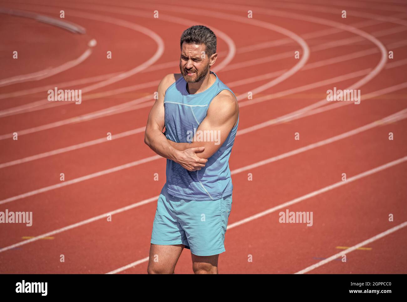man has injury after exercise on stadium. fitness gym outdoor. muscular ...
