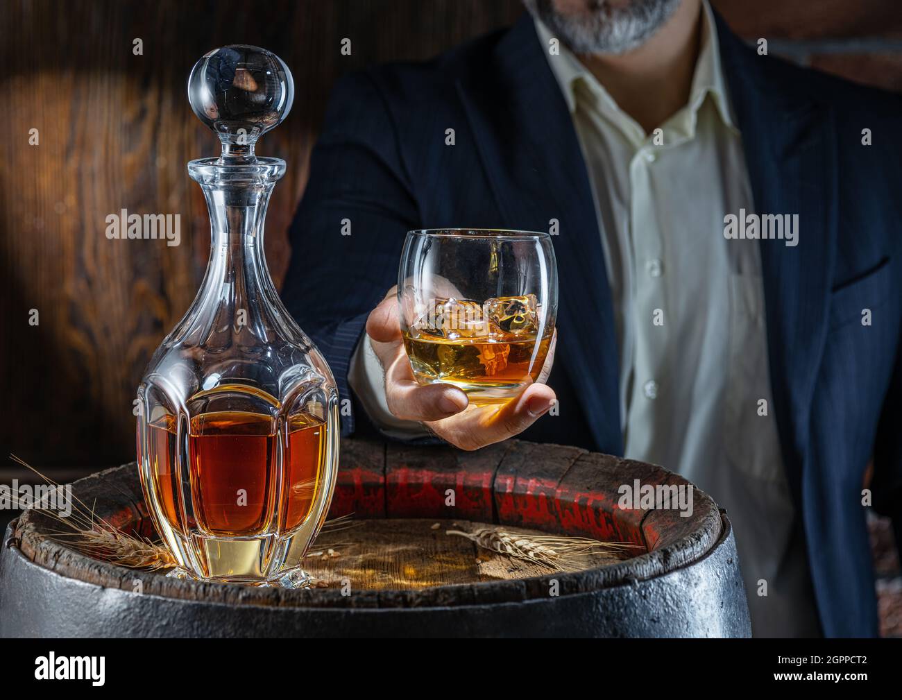 Whisky tasting. Man sits in front of a barrel with a decanter and a ...