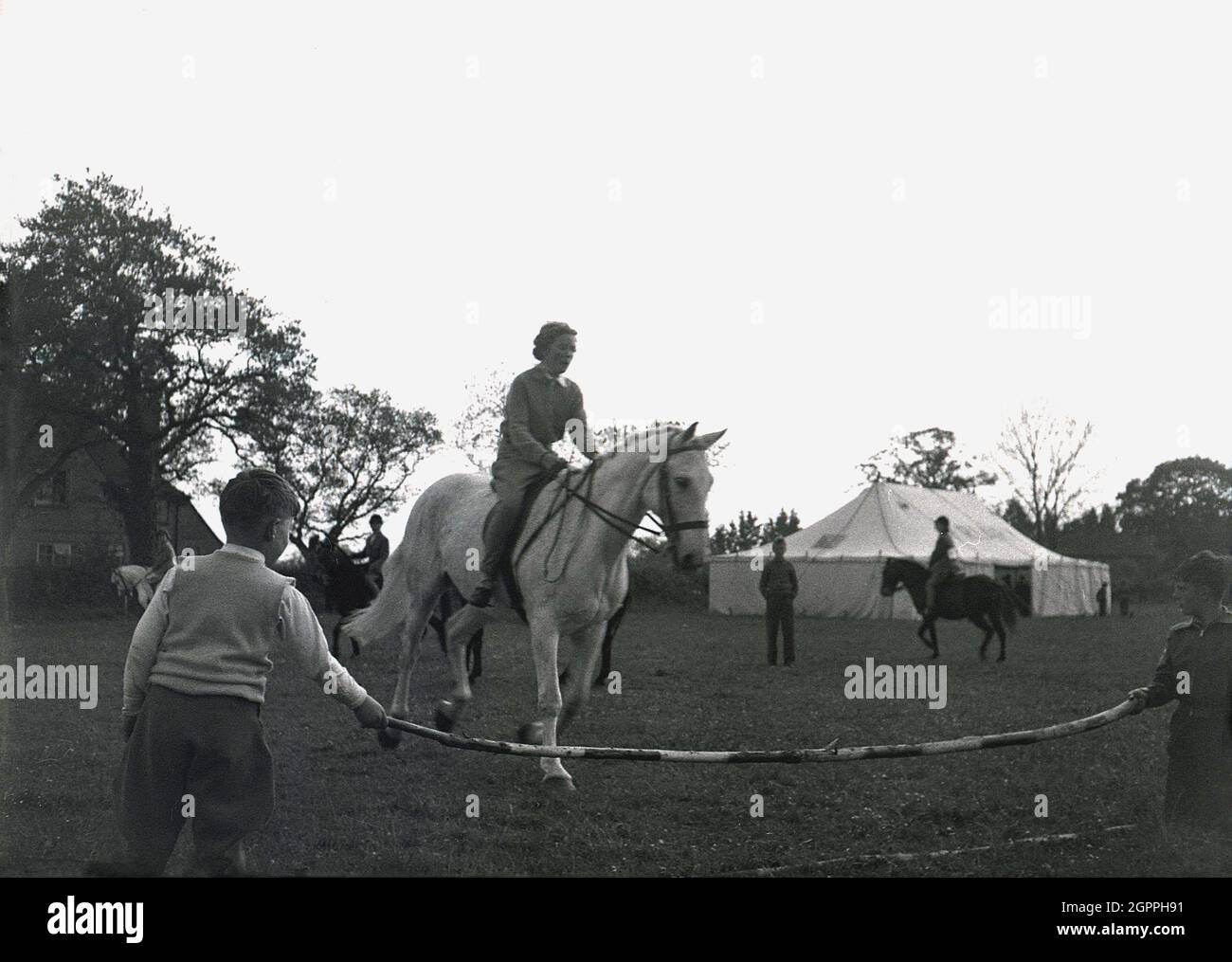 1950s, historical, outside in a field at at a equestrian event, a lady ...