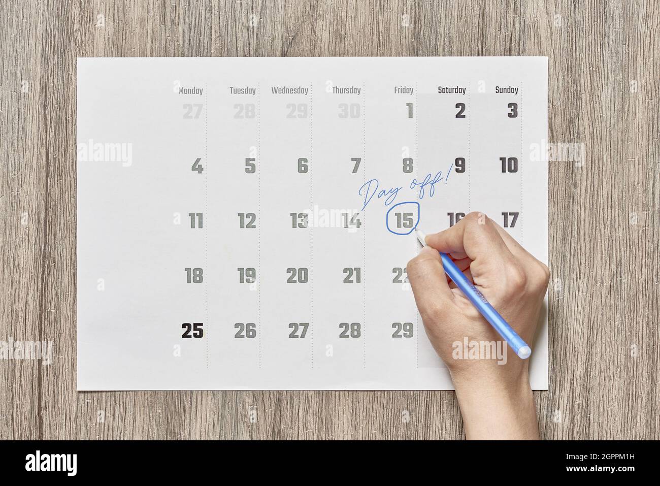 Calendar with a circled date and day off text on a wooden background ...