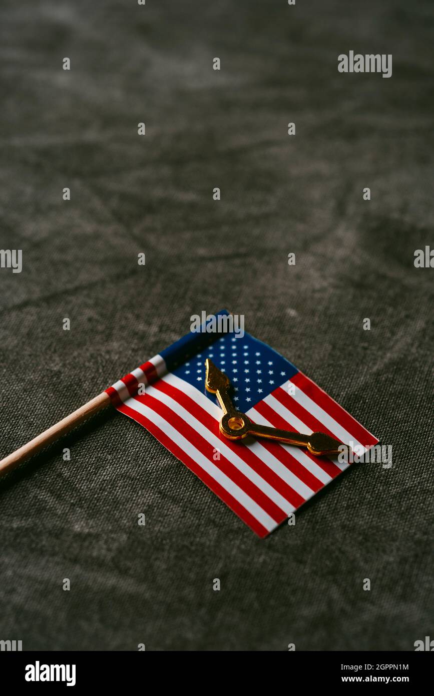 clock hands on a flag of the Uniteds States of America on a dark gray ...