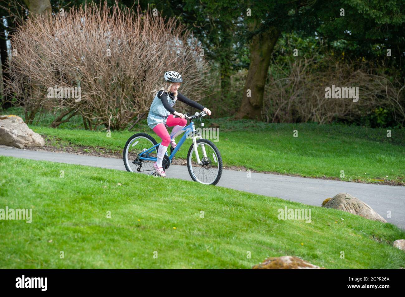 A Young Girl Rides A Bike Along A Country Road Wearing A Cycle Helmet ...