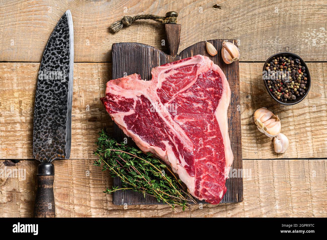 Raw Porterhouse or T-bone beef meat Steak with herbs on a wooden ...