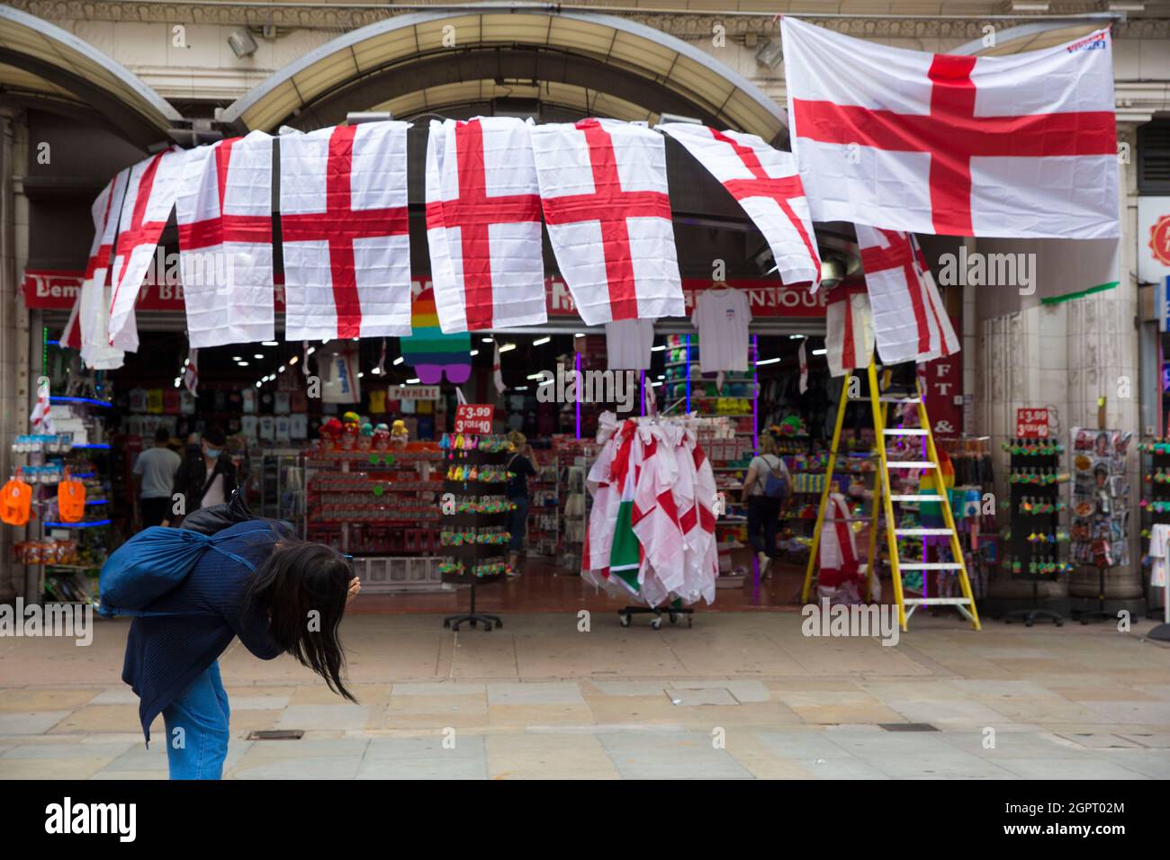 A person takes photographs of England flags seen at a shopfront in ...
