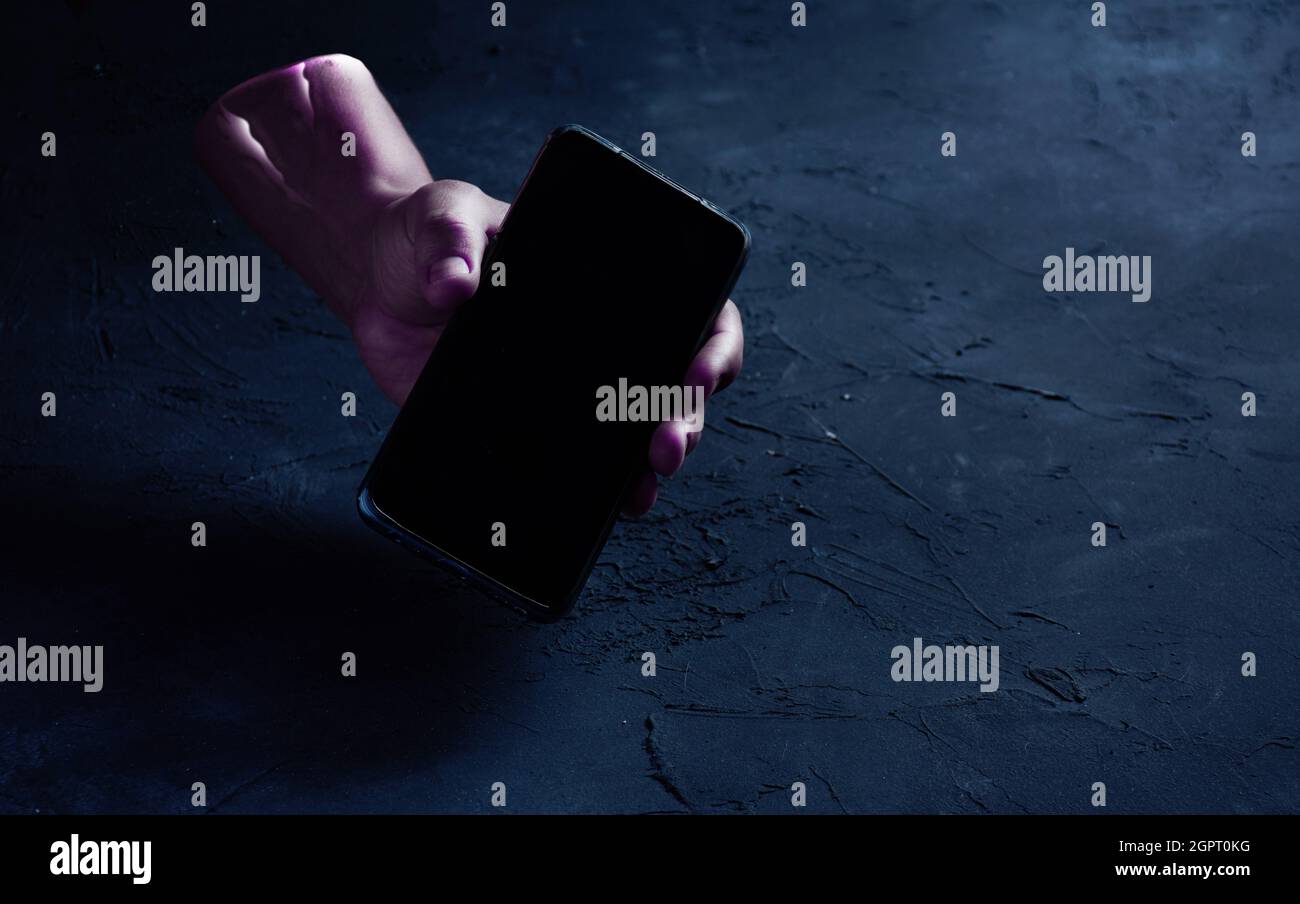 Creepy severed human hand holding a smartphone in an eerie setting on a ...