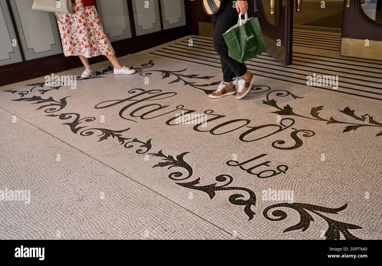Customers with sign outside with brand name of the world famous Harrods ...