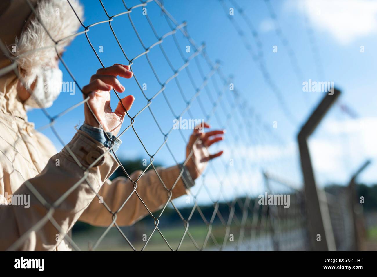 Lady's hand clinging to wire mesh, Behind the barrier Stock Photo - Alamy