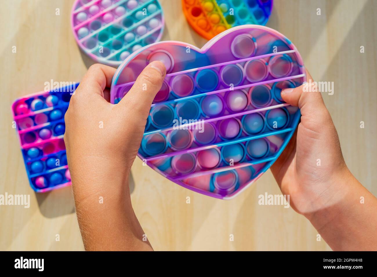 Little child playing with anti stress sensory pop it at wooden table ...