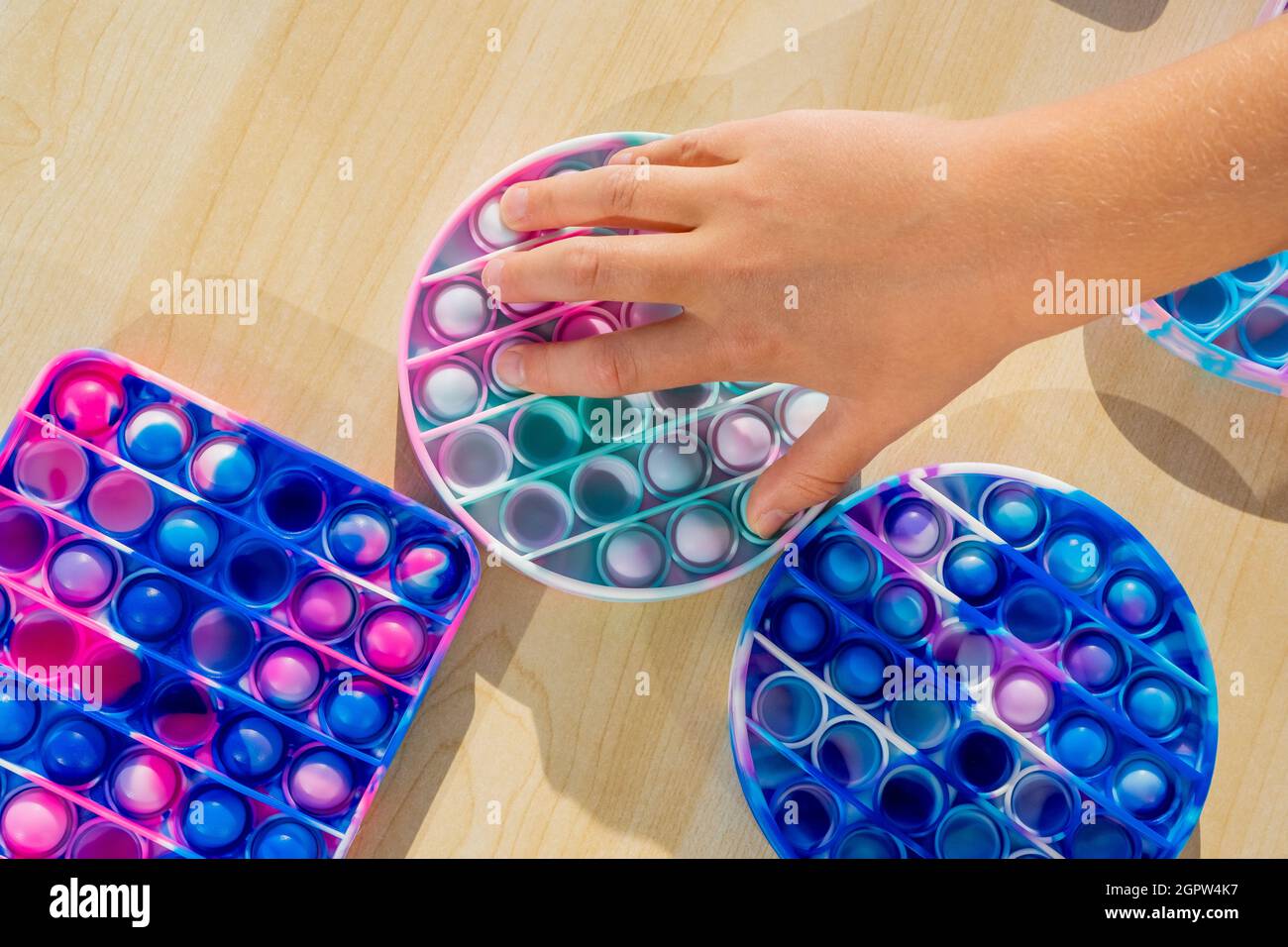 Little child playing with anti stress sensory pop it at wooden table ...