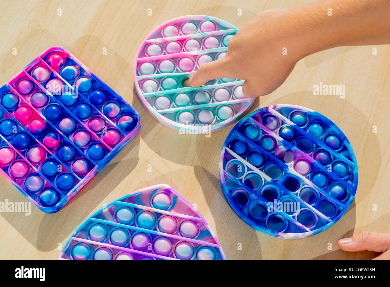 Little child playing with anti stress sensory pop it at wooden table ...
