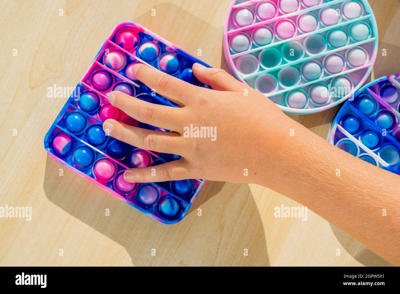 Little child playing with anti stress sensory pop it at wooden table ...