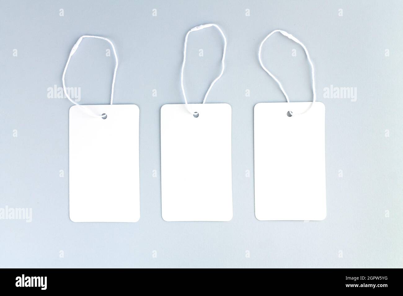 Set of three blank white paper cloth labels or price tags on gray ...