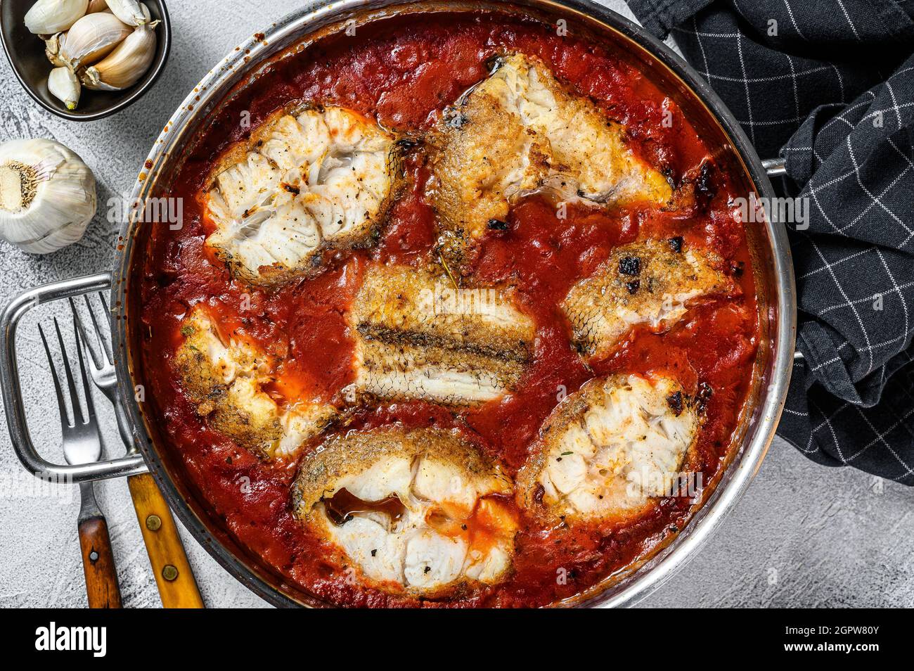 Baked grenadier macrurus white fish with tomato in a pan. White Wooden ...