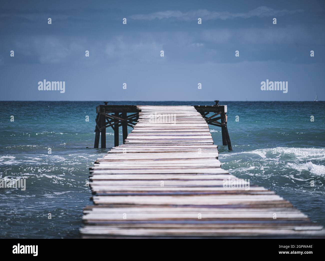 Beautiful shot of a wooden dock (pier) in the sea with waves on a ...
